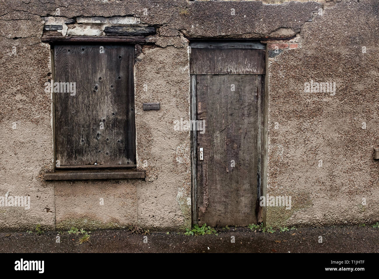 Exterior shots of crumbling grey rough cast wall in and around the ...