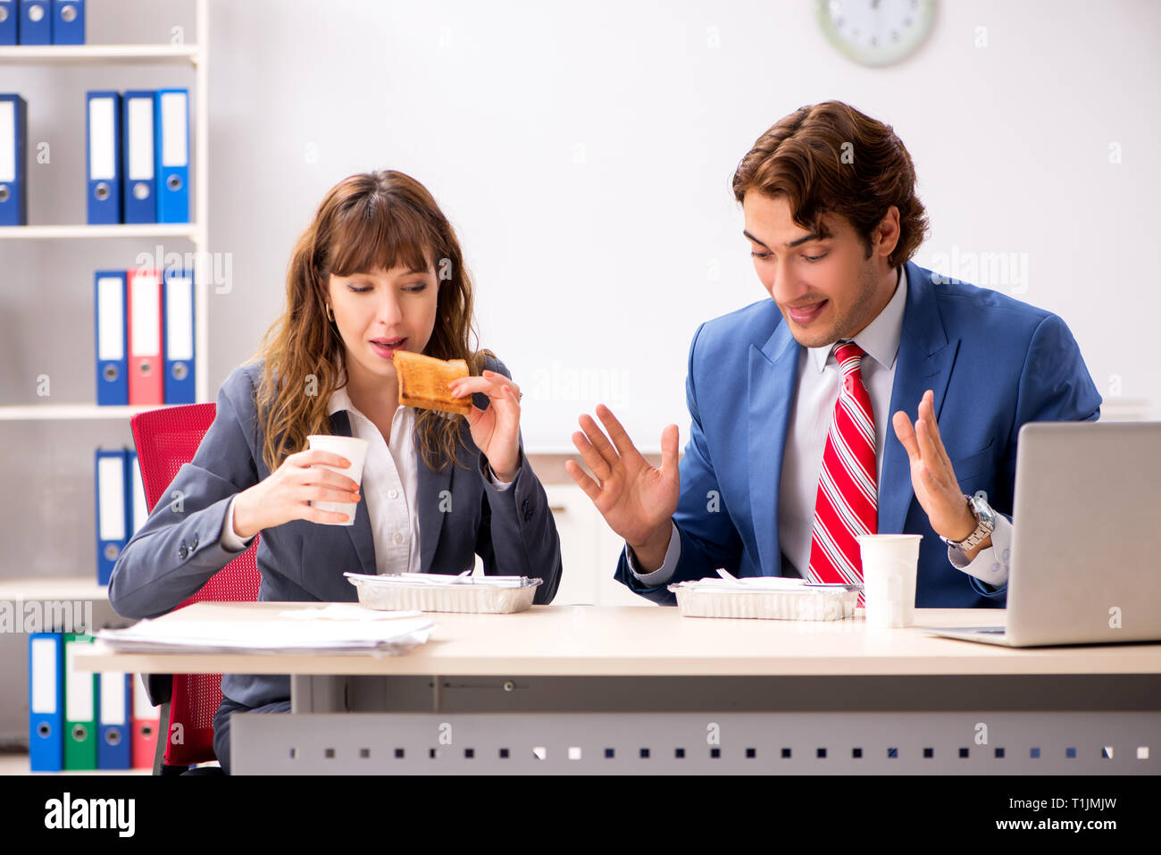 Two colleagues having lunch break at workplace Stock Photo - Alamy