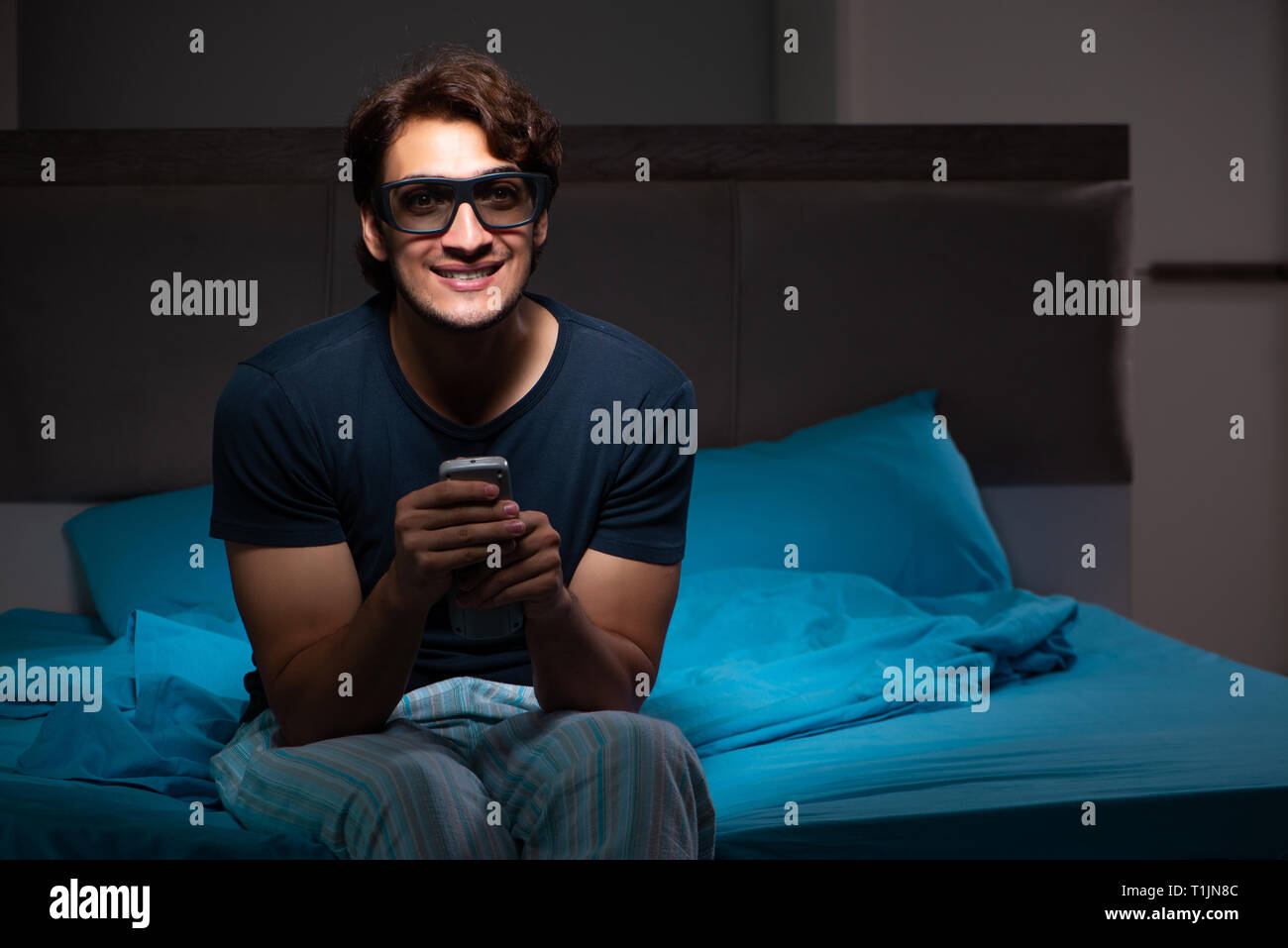 Man watching tv at night in bed Stock Photo - Alamy