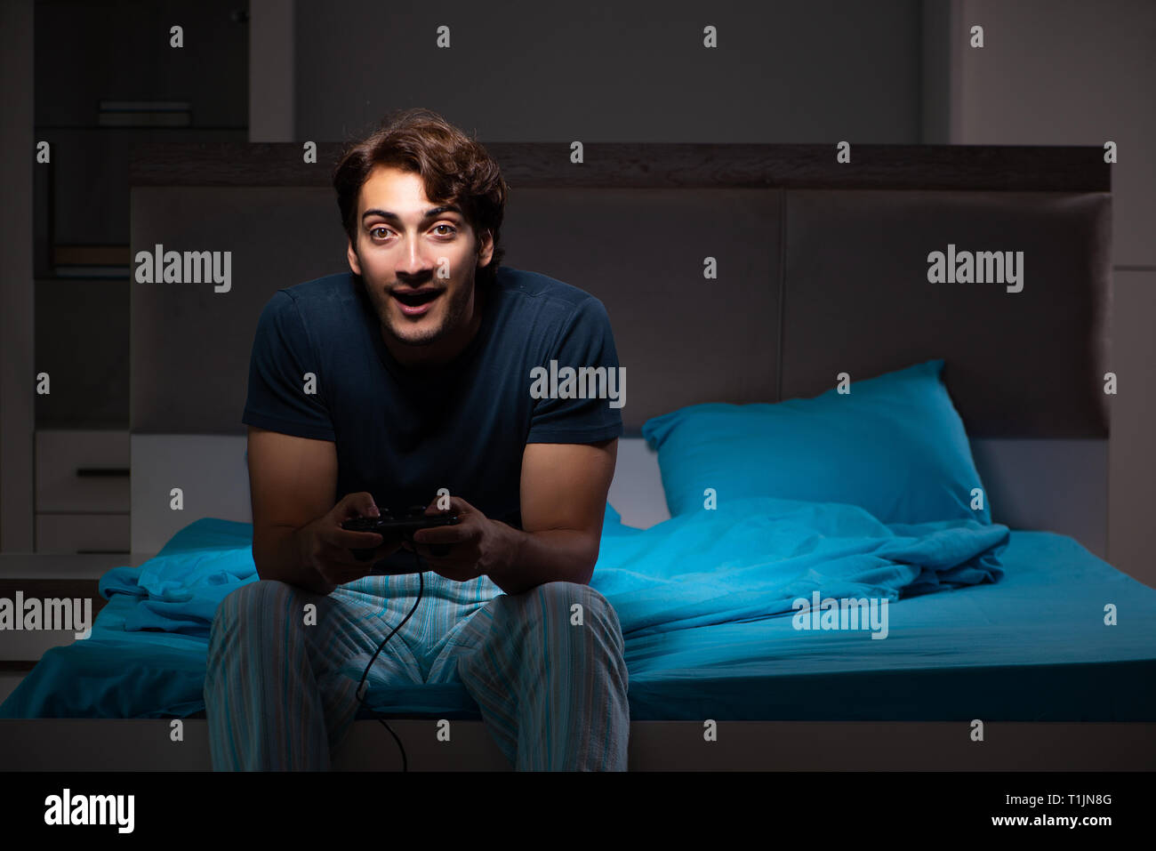 Young man playing computer games at night in bed Stock Photo - Alamy