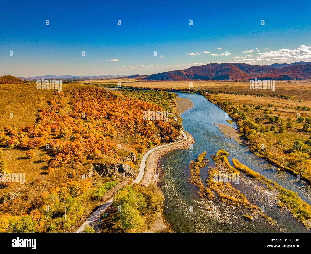 Aerial photograph of meandering river against mountains and grasslands ...