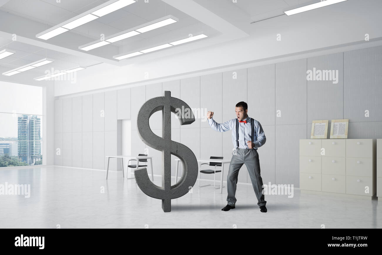 Determined banker man in modern office interior breaking dollar figure ...