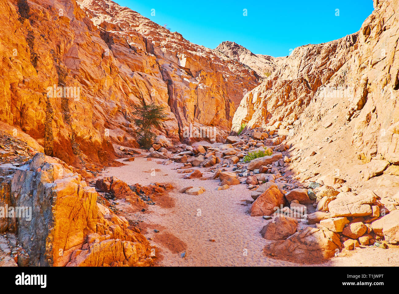 Walk along the curved path in Small Colored canyon with steep red rocks ...