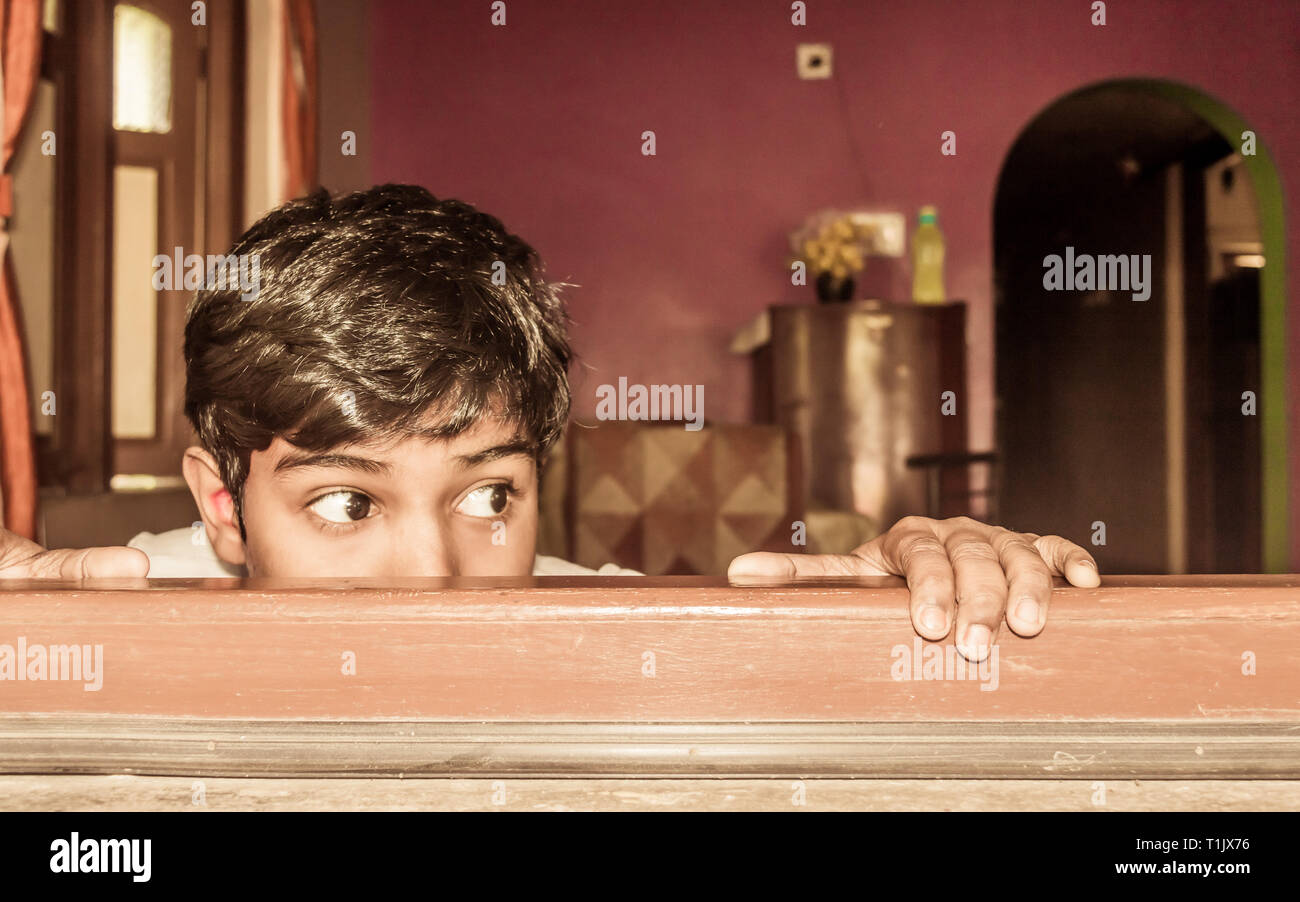 Young boy curiously looking outside through a window Stock Photo - Alamy