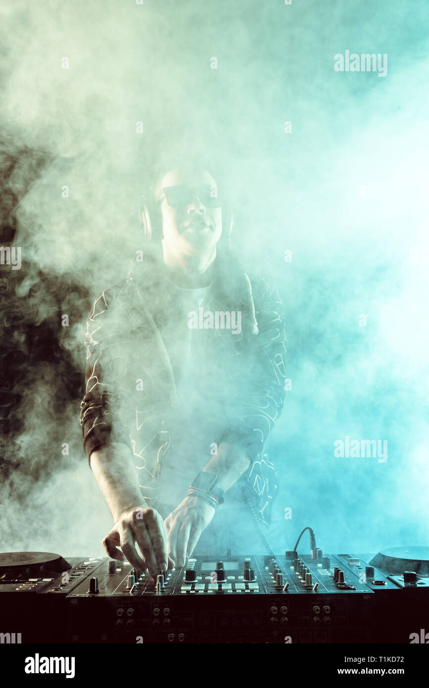 DJ mixing music on mixer on dark background Stock Photo - Alamy
