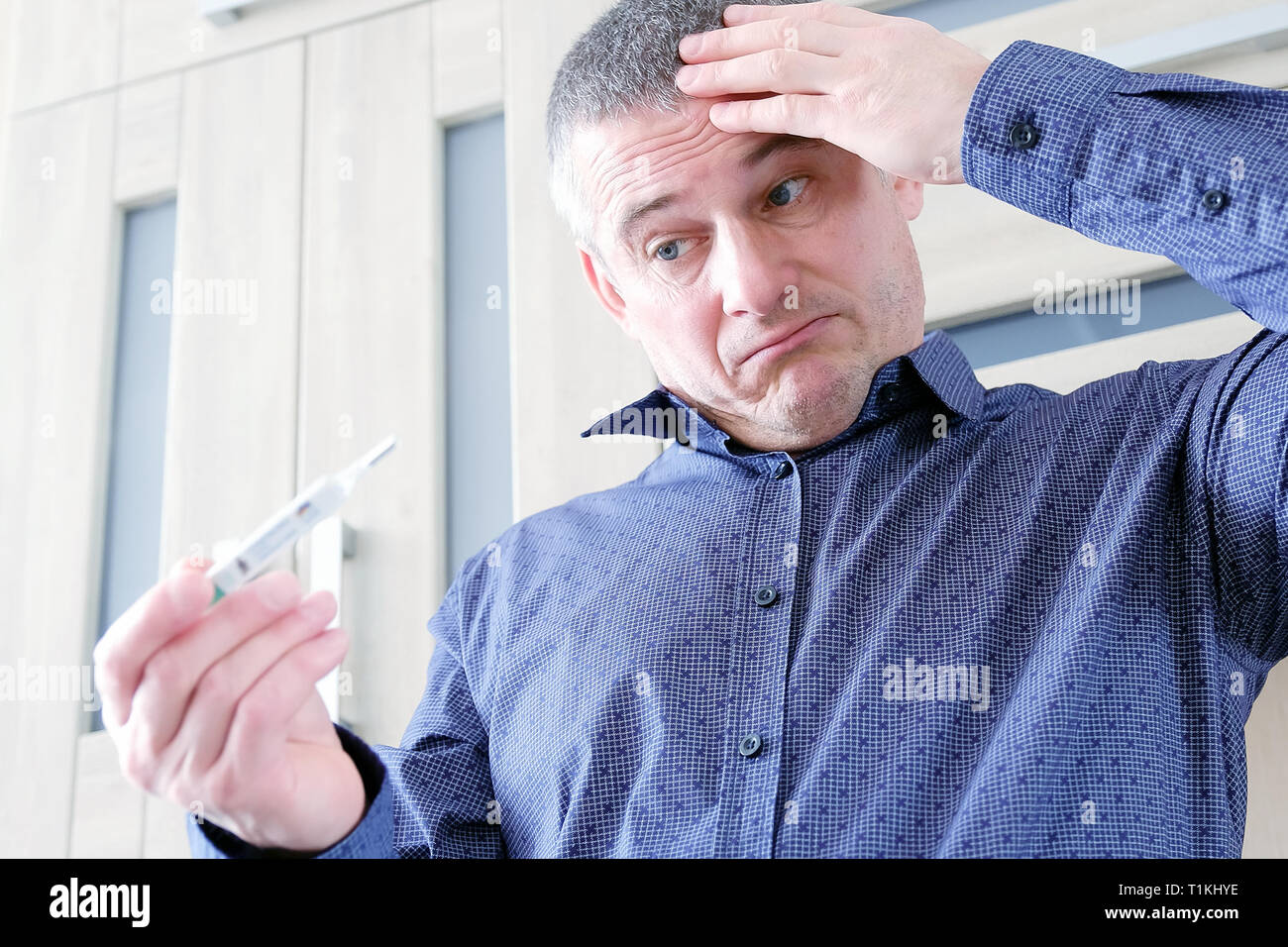 A Man Holding A Thermometer In His Hands Measuring Body Temperature