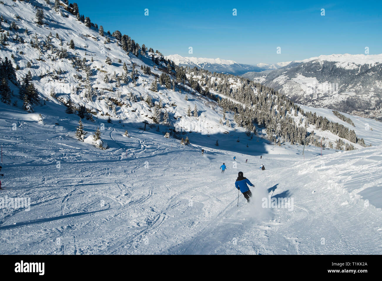 Panoramic landscape valley view with skiers going down a ski slope ...