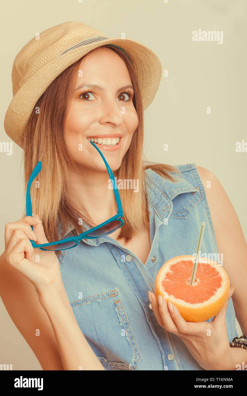 Happy glad woman tourist in straw hat holding sunglasses and grapefruit ...