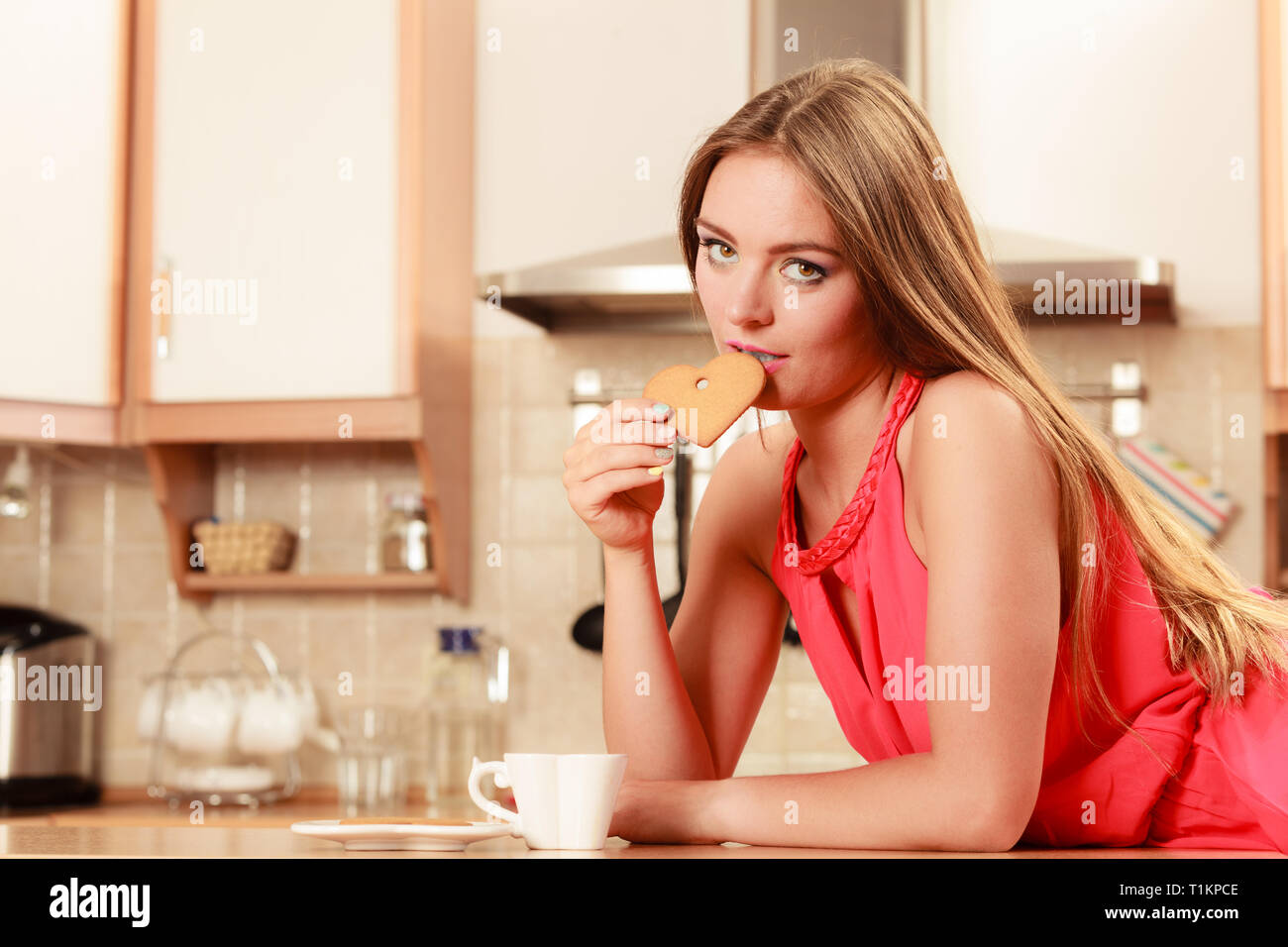 Pretty woman with tea or coffee eating heart shape gingerbread cookie ...