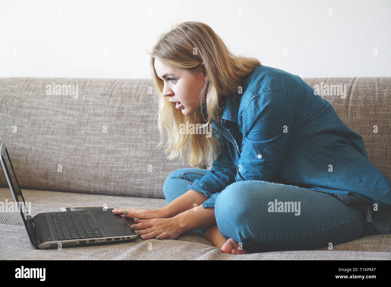 Shocked young woman looking at laptop screen at home seeing something ...