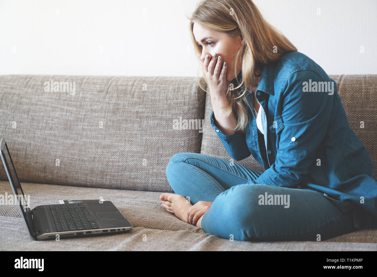 Shocked young woman looking at laptop screen at home seeing something ...