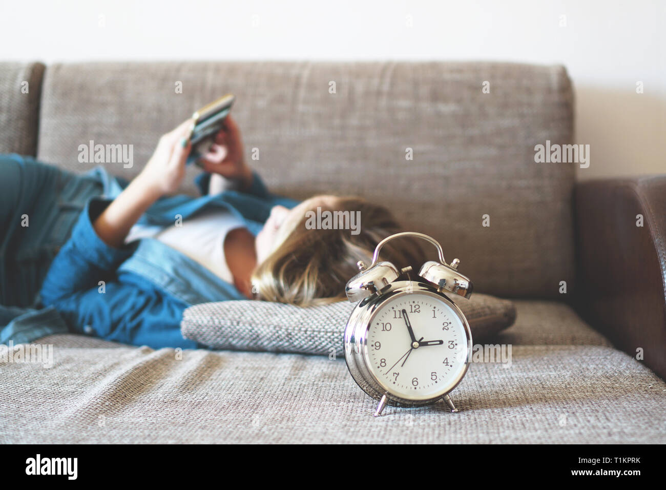 Young woman using phone in bed, looking at screen, insomnia, check time ...