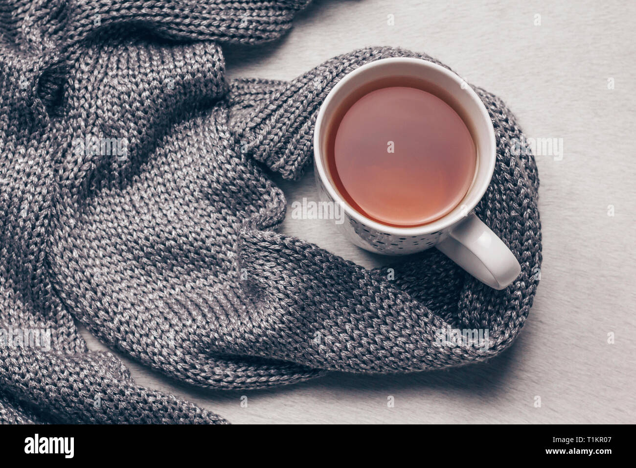 Stylish silvery grey knitted fabric along a cup of tea on milky white ...