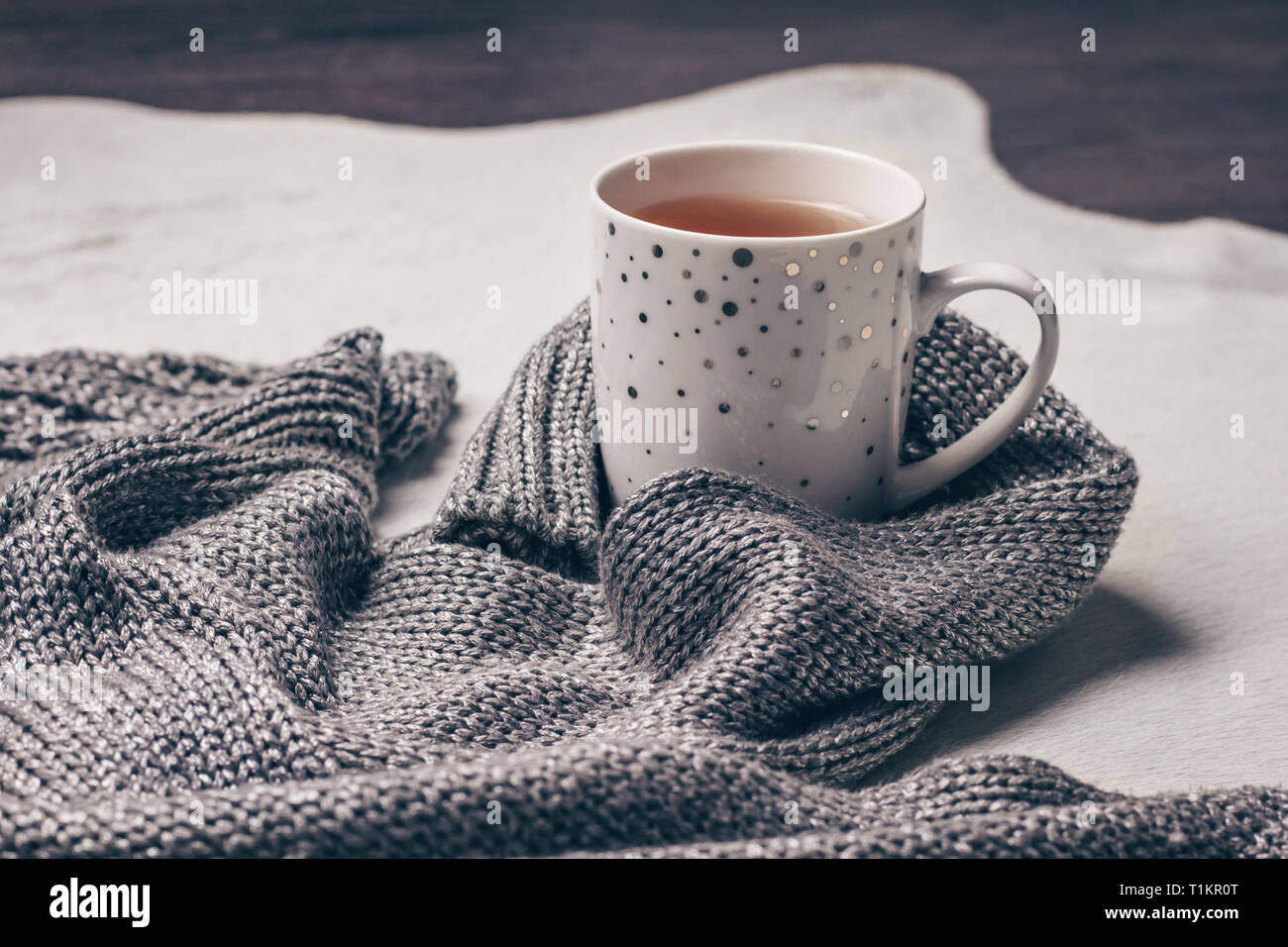Stylish silvery grey knitted fabric along a cup of tea on milky white ...