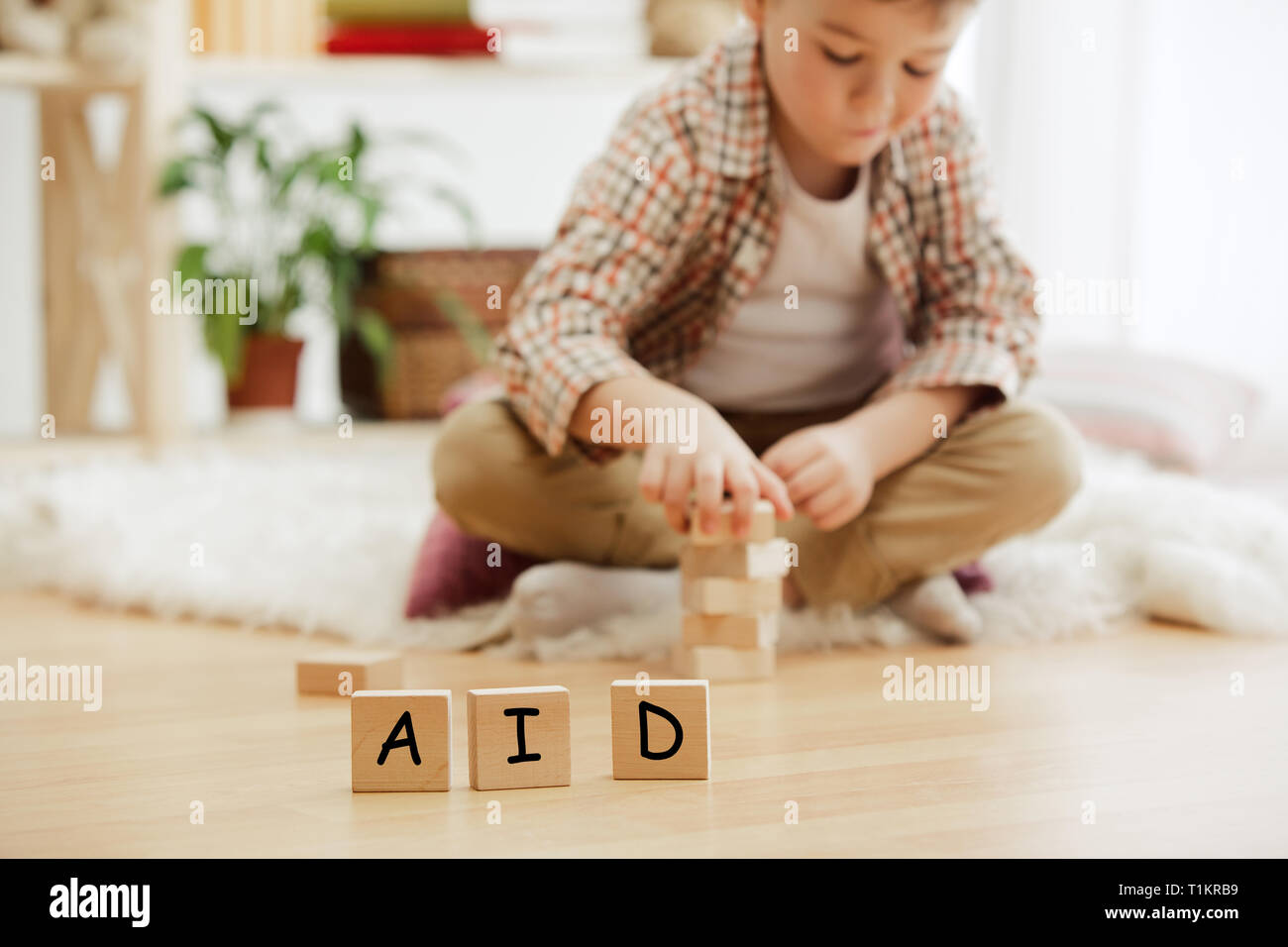 Wooden cubes with word AID in hands of little boy at home. Symbol of ...