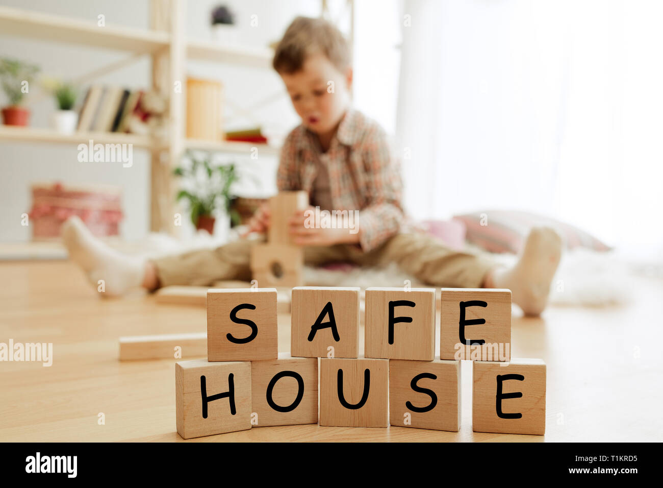 Wooden cubes with words SAFE HOUSE in hands of happy smiling little boy ...