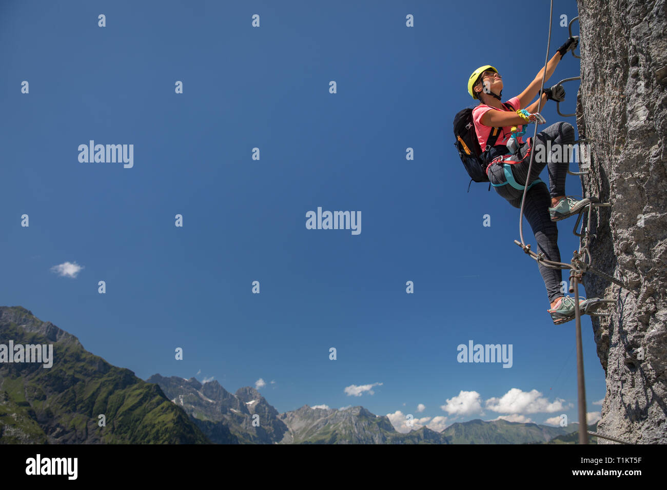 Pretty, female climber on a via ferrata - climbing on a rock in Swiss ...