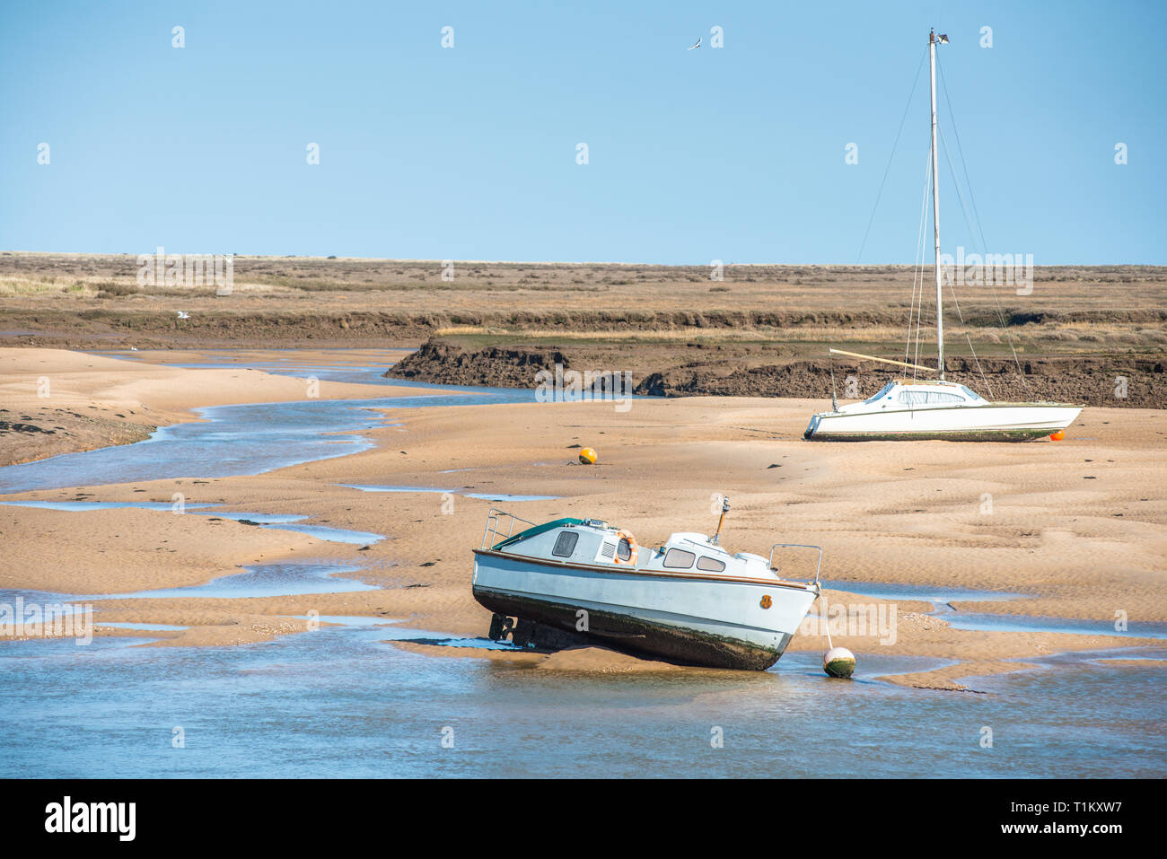 Colourful boats marooned on sandbanks at low tide on East Fleet river ...