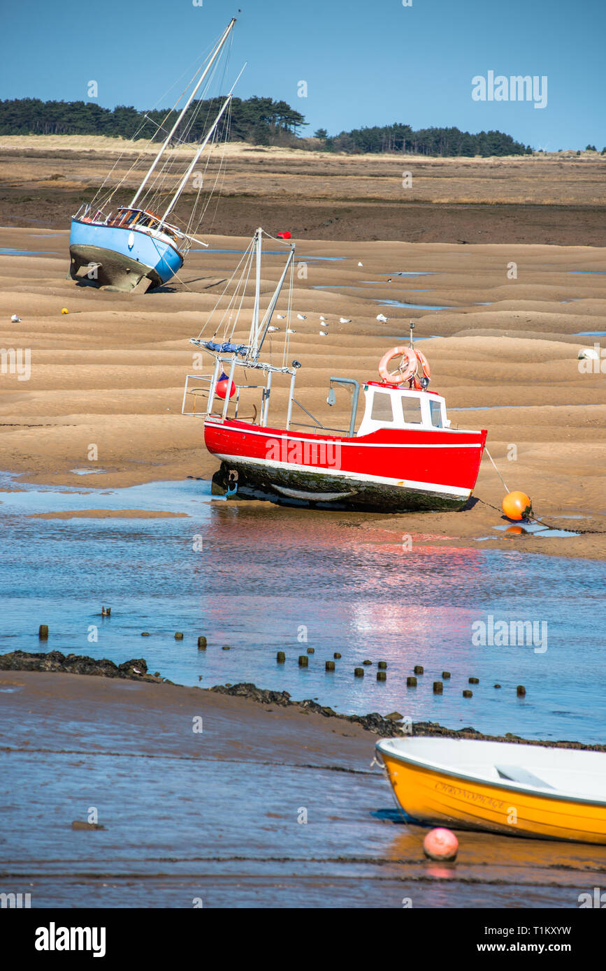 Colourful boats marooned on sandbanks at low tide on East Fleet river ...
