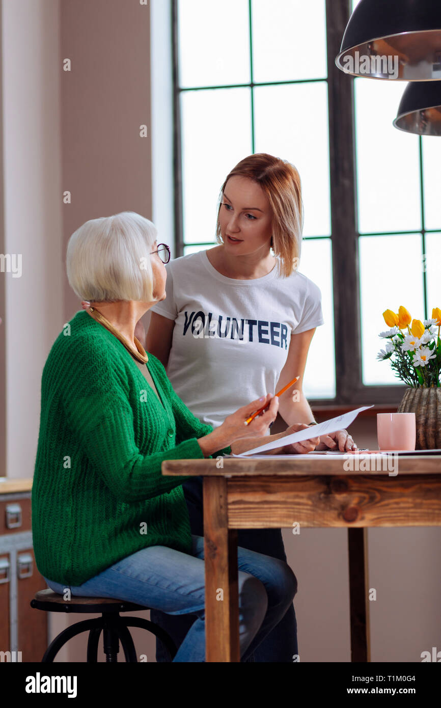 Charming lady having discussion with young-adult girl about documents ...