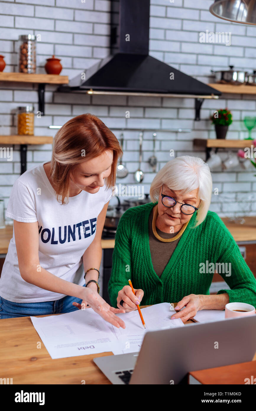 Appealing elderly woman asking young-adult lady for helping with papers ...