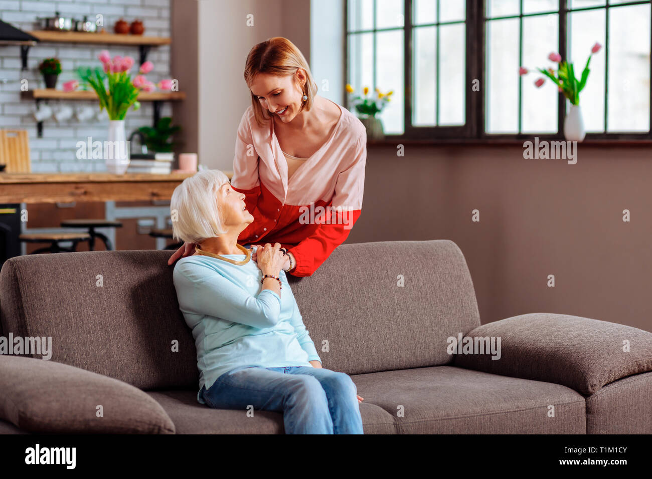 Graceful elderly mom with grey hair lovingly holding daughter palm ...