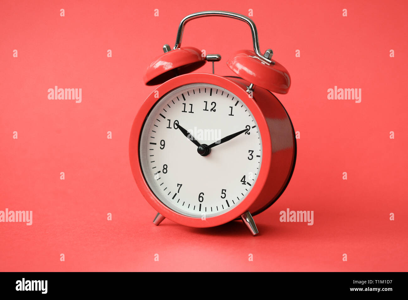 Coral old alarm clock on red background Stock Photo - Alamy