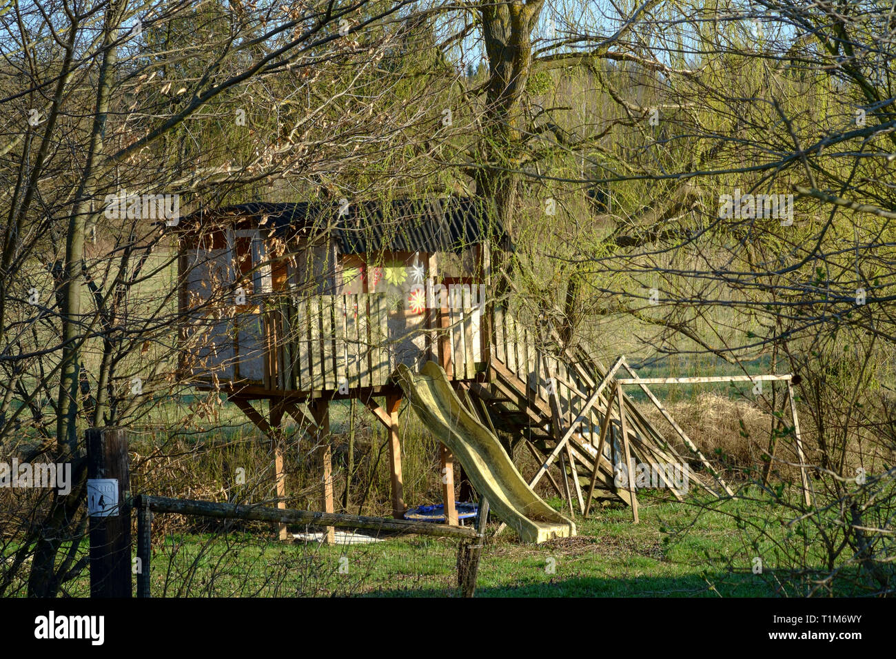 home made wooden tree house on stilts in the garden of a rural village ...
