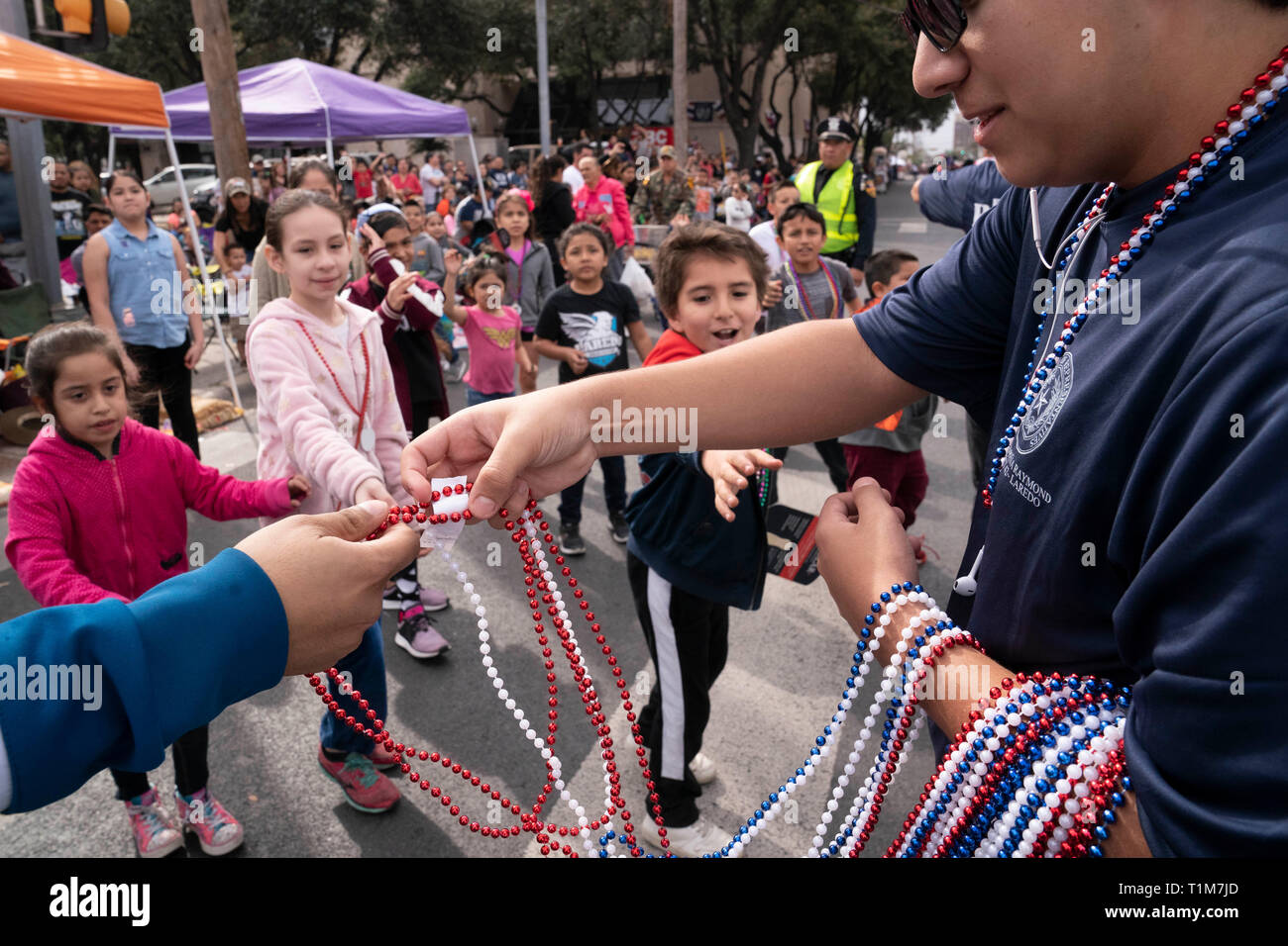 Volunteer hands out souvenir beads to kids on parade route during ...