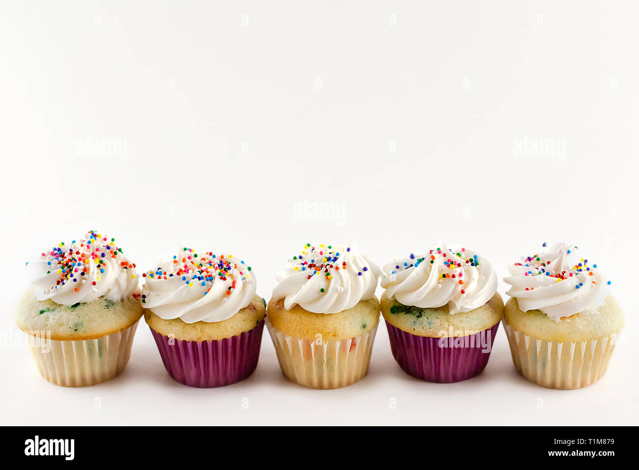 Five mini cupcakes in a row isolated on white background. Confetti cake ...