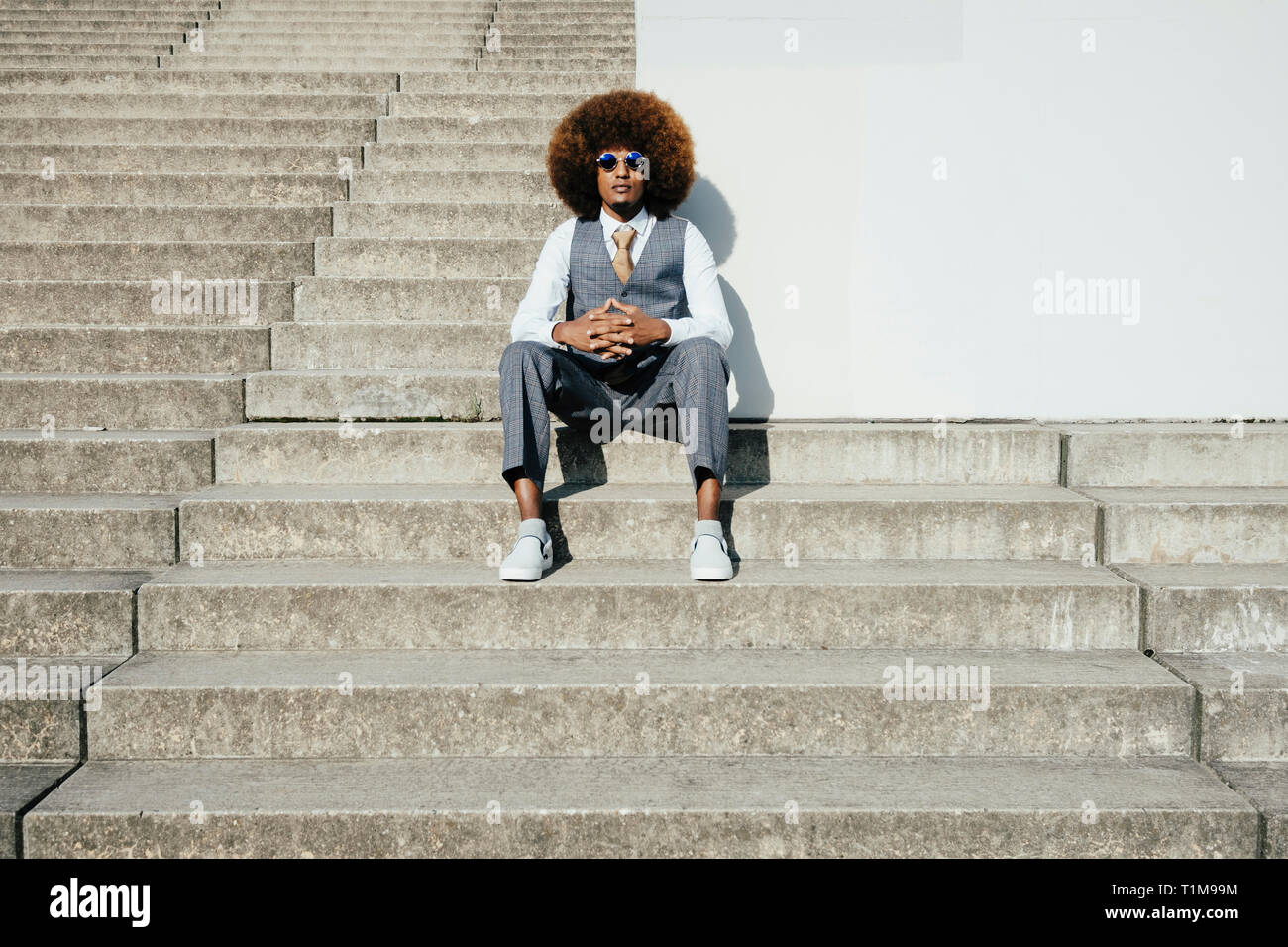 Portrait confident, cool, well-dressed young man with afro sitting on ...