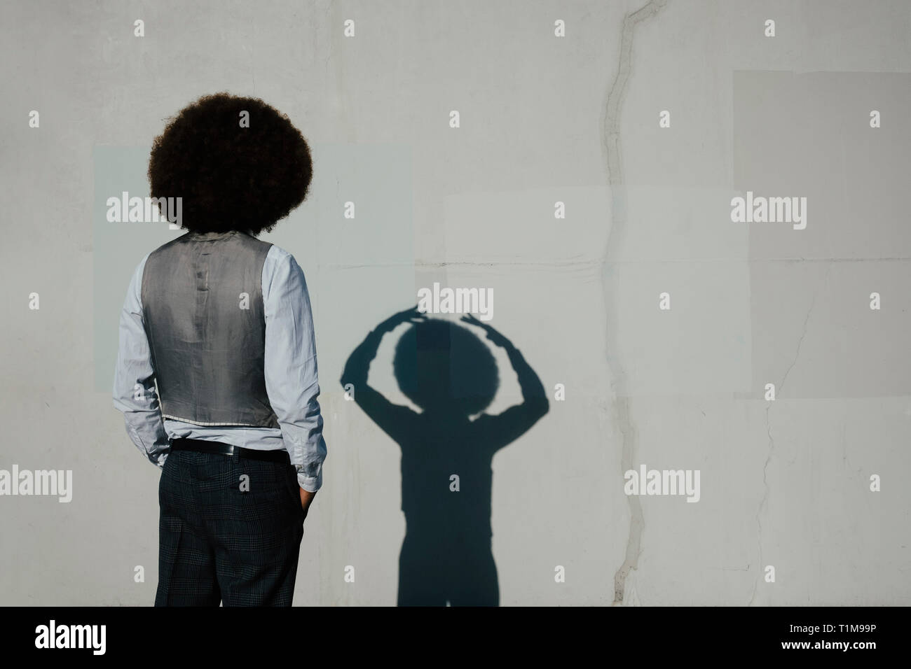 Young man with afro watching gesturing shadow on sunny wall Stock Photo ...