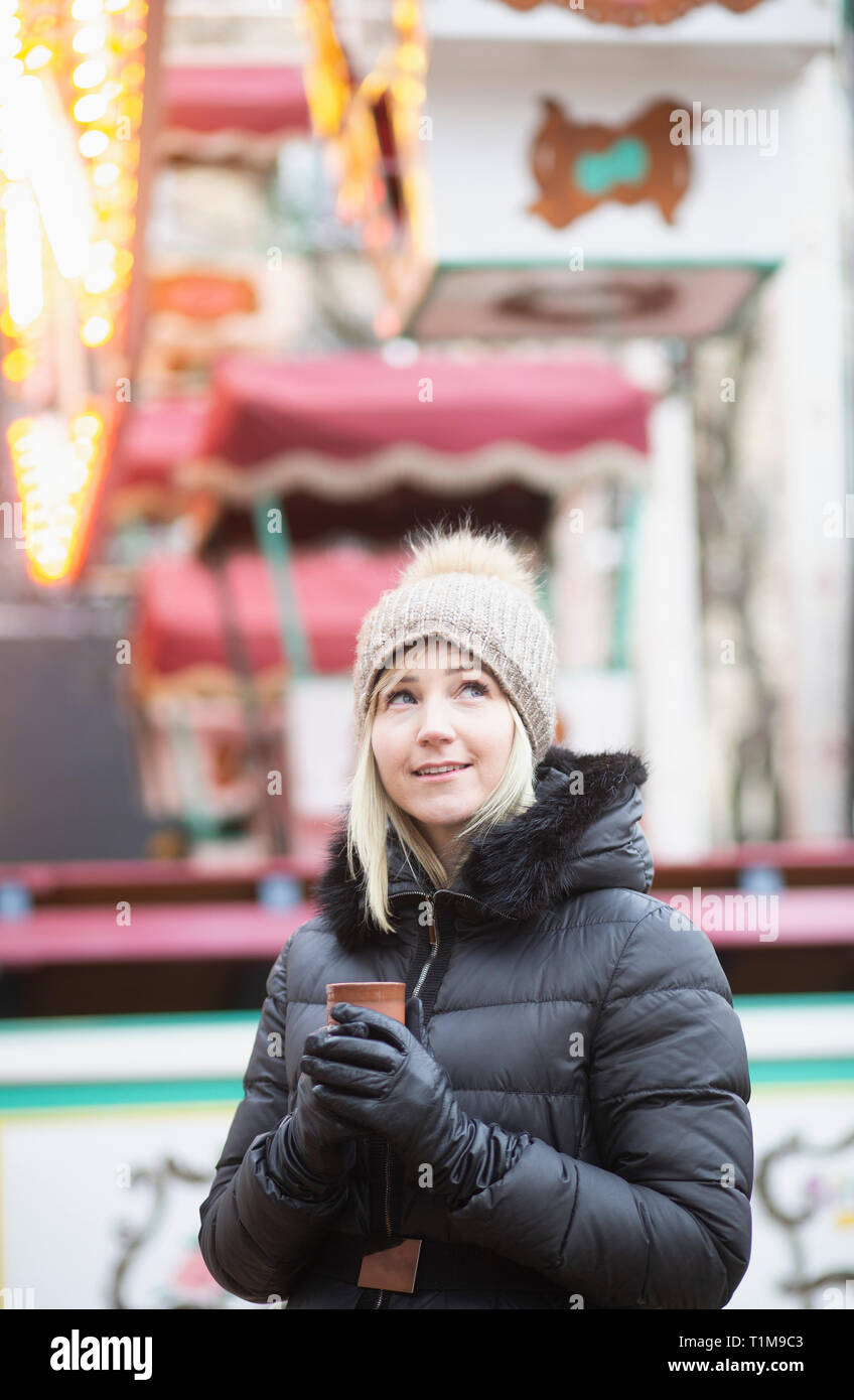 Woman in warm clothing drinking tea at carnival Stock Photo - Alamy