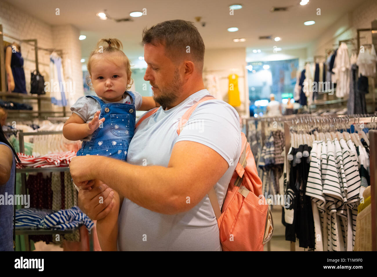 dad with child girl chooses and buys clothes in the store, concept of ...