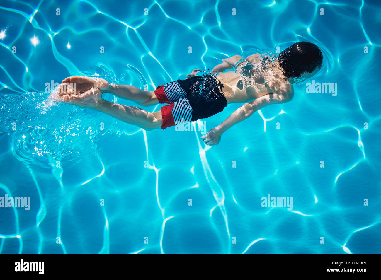 Boy swimming in blue swimming pool Stock Photo - Alamy