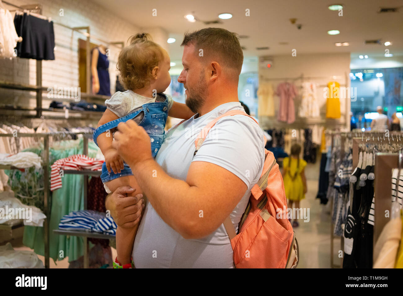 dad with child girl chooses and buys clothes in the store, concept of ...