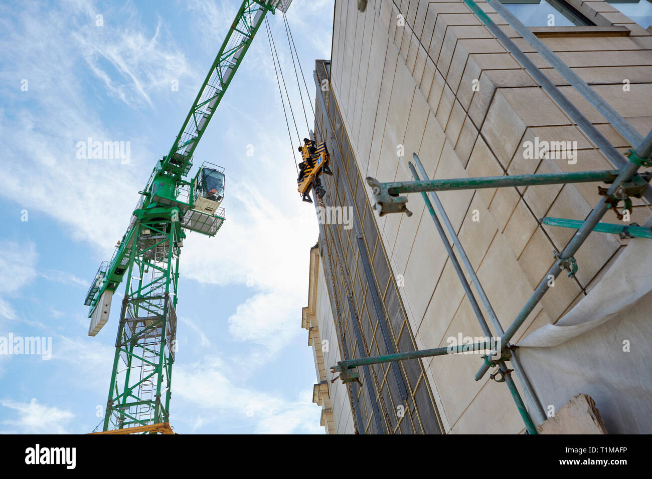 Tower crane lifting construction materials Stock Photo - Alamy