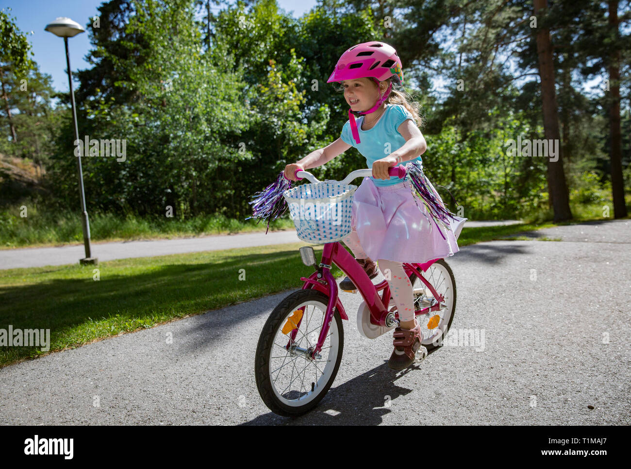 Cute little girl riding bike. Happy active kid. Sunny summer day on ...
