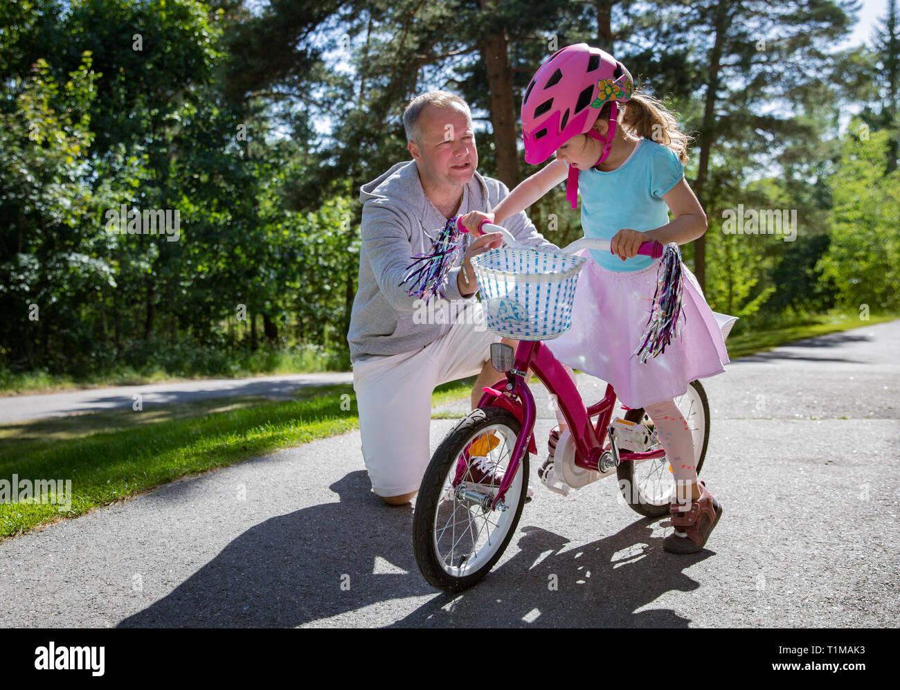 Father teaching his daughter to ride bicycle. Happy kid learning riding ...