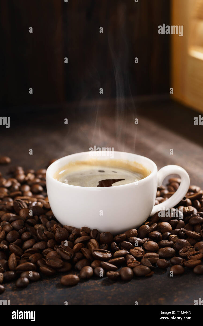 Cup of hot coffee with steam and roasted coffee beans. Dark background ...
