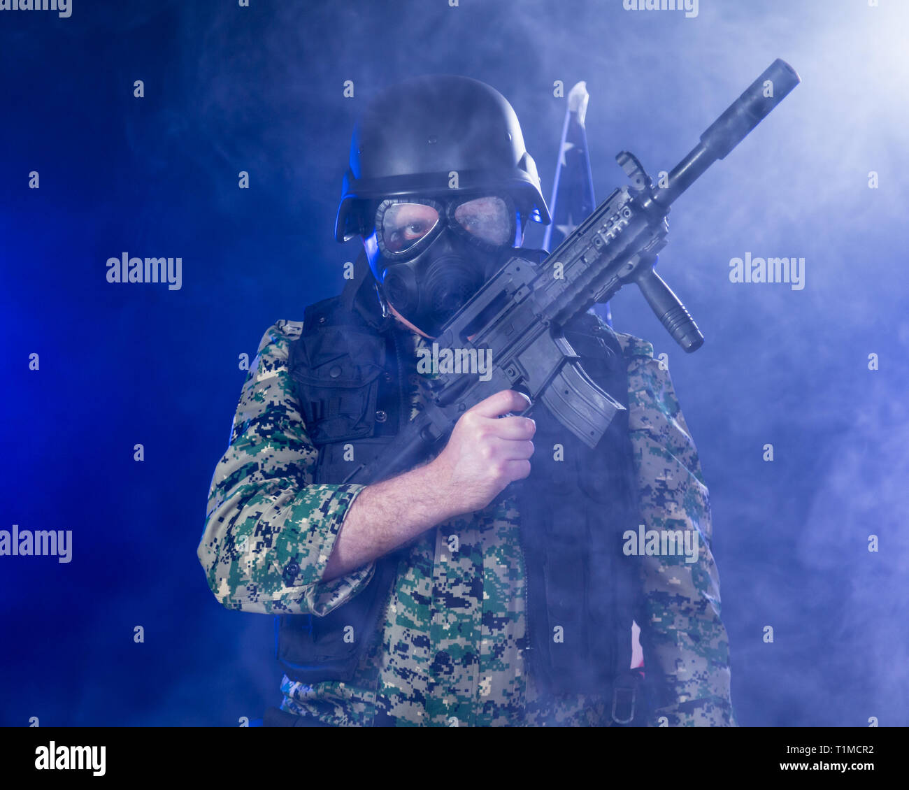 Soldier in army fatigues wearing gas mask holding assault rifle in haze ...