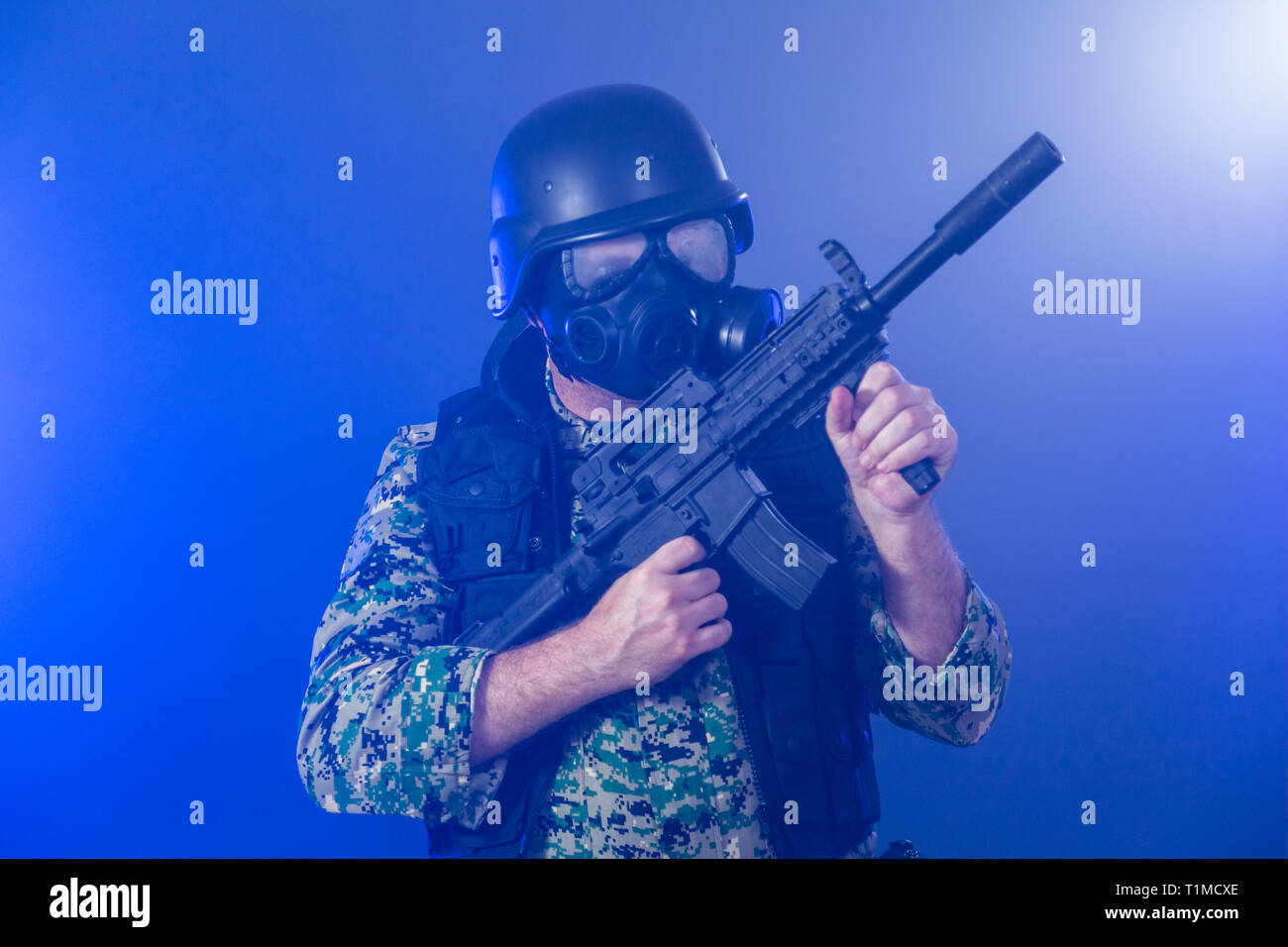 Soldier in army fatigues wearing gas mask holding assault rifle in haze ...