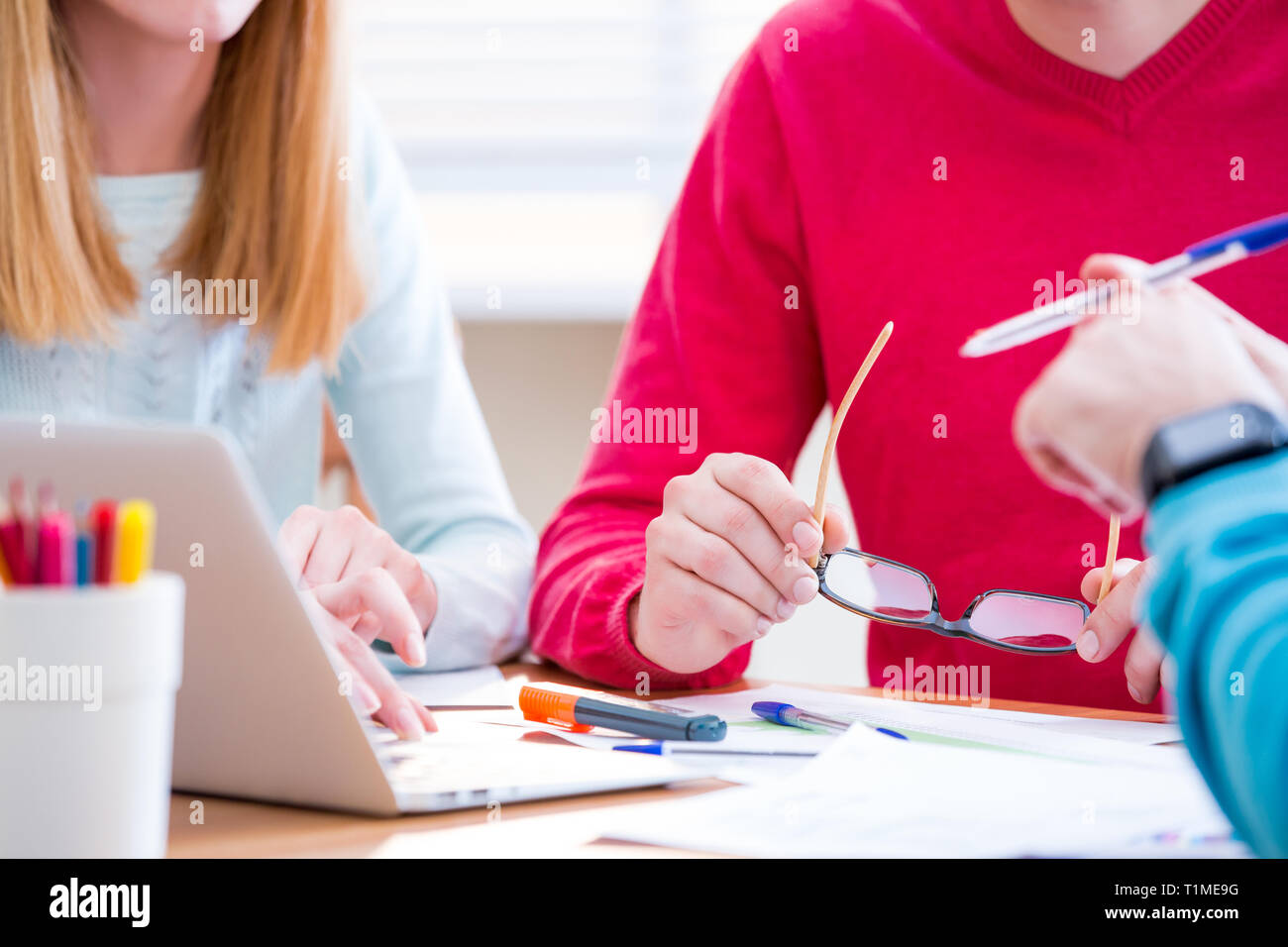 Young people discussing projects and ideas sitting around table with ...