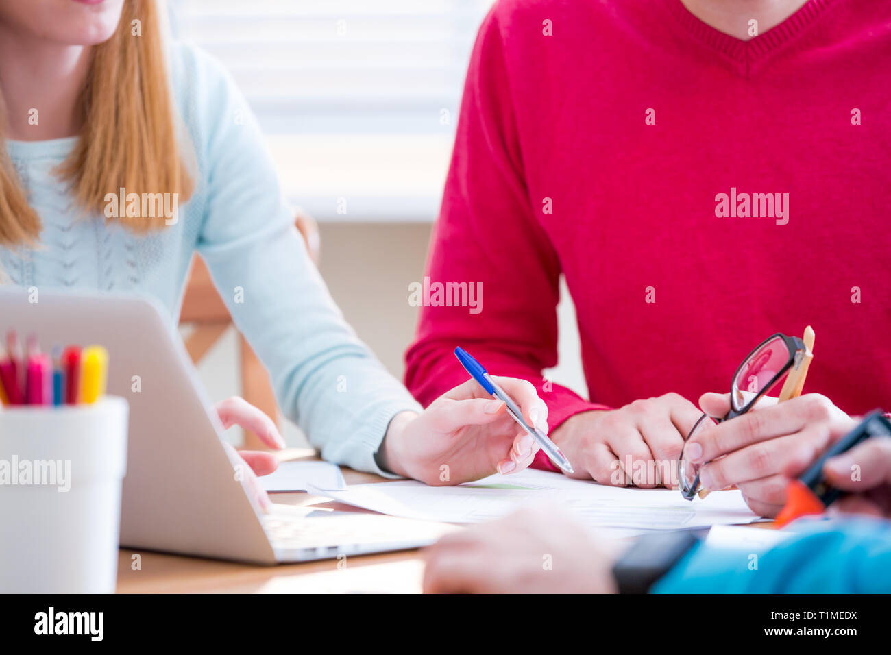Young people discussing projects and ideas sitting around table with ...