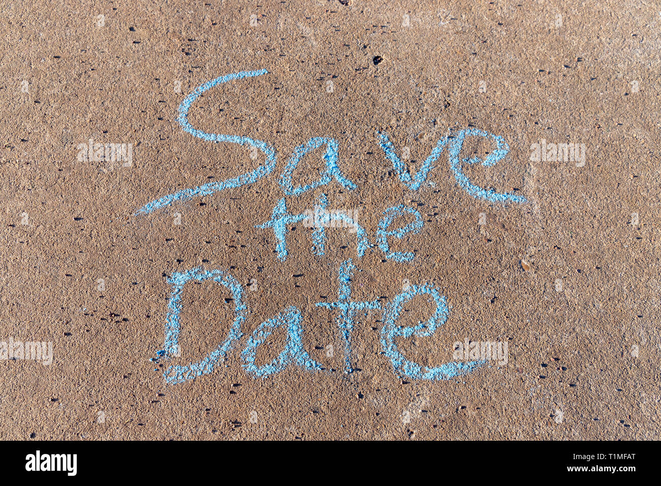the words Save the Date written with sidewalk chalk on gray concrete ...
