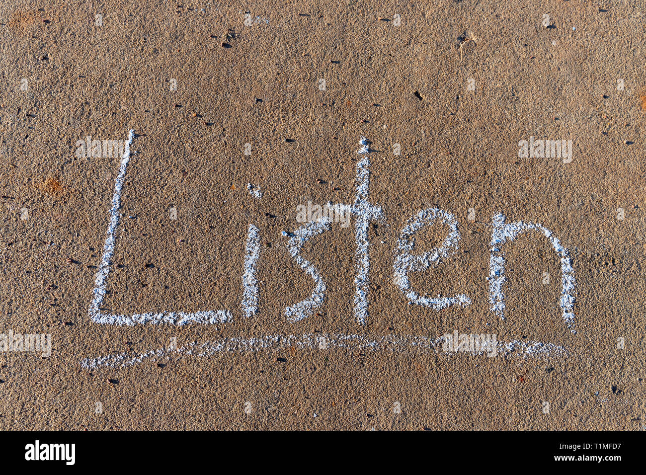 the word Listen written with sidewalk chalk on gray concrete pavement ...