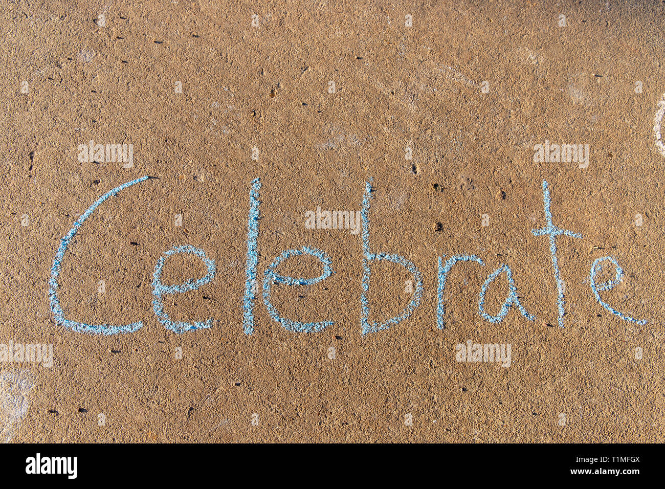 the word Celebrate written with sidewalk chalk on gray concrete ...