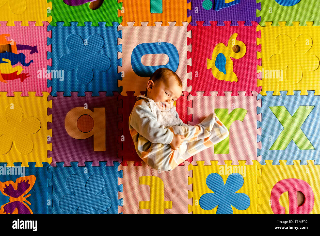 Adorable smiling baby seen from above in pajamas, lying on his back in ...