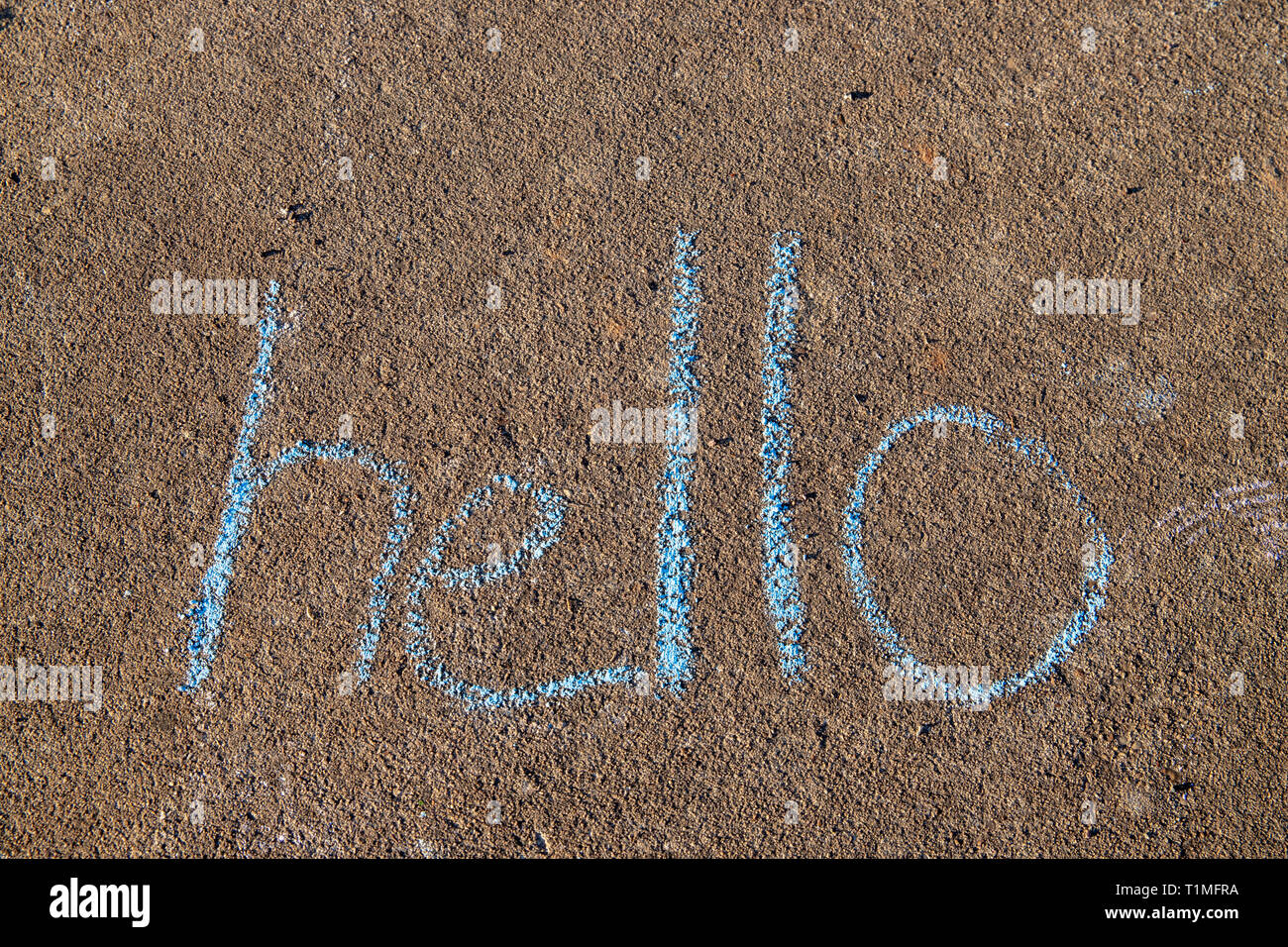 the word Hello written with sidewalk chalk on gray concrete pavement ...