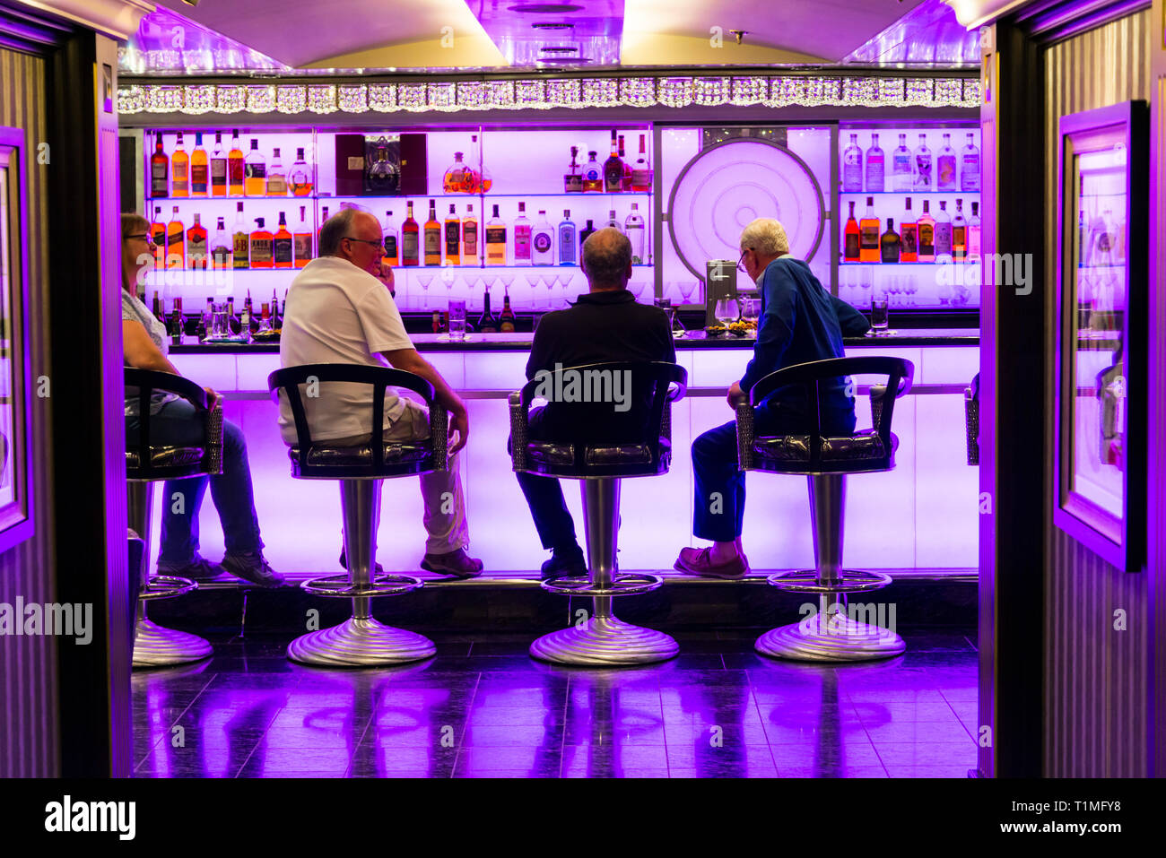 Adults sitting and drinking beer, wine, and alcohol at a colorful bar ...